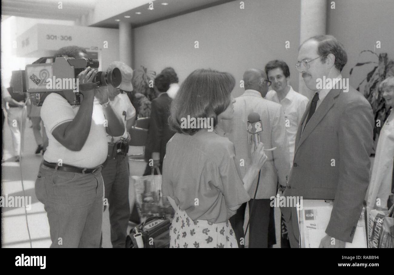 A FEMALE NEWS REPORTER IS INTERVIEWING A MAN WITH OTHER PEOPLE IN THE ...