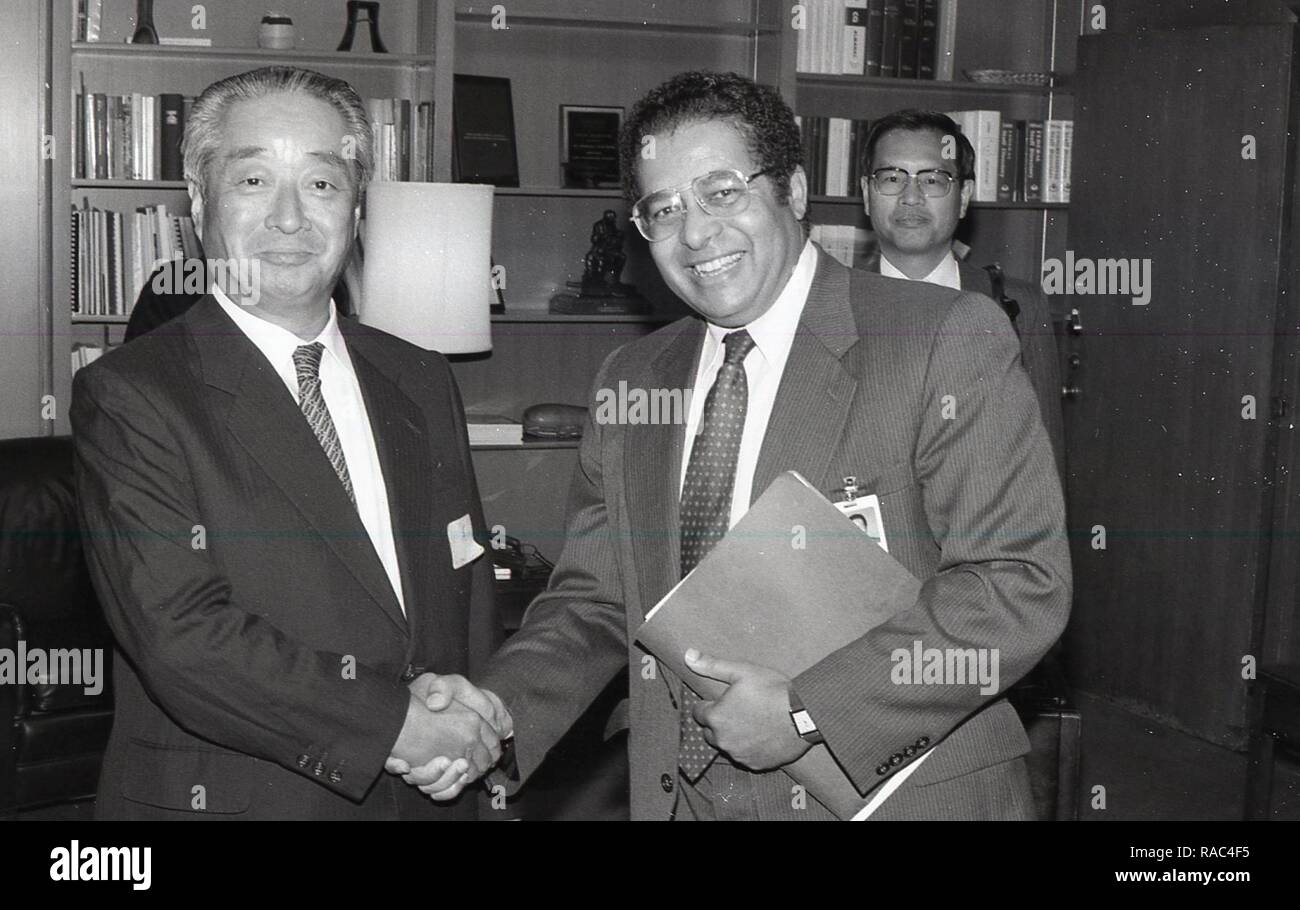 TWO MEN GREETING EACH OTHER WITH ANOTHER MAN STANDING IN THE BACK Stock ...