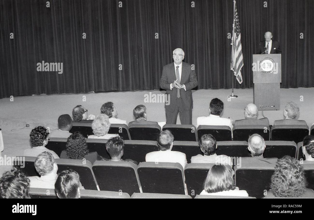 MAN STANDING TALKING TO A GROUP OF MEN AND WOMAN WITH ANOTHER MAN AT ...