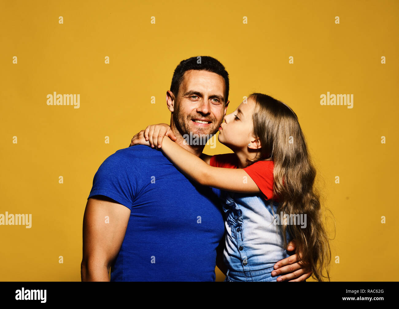 Man and girl hug on yellow background. Father and child with smiling ...