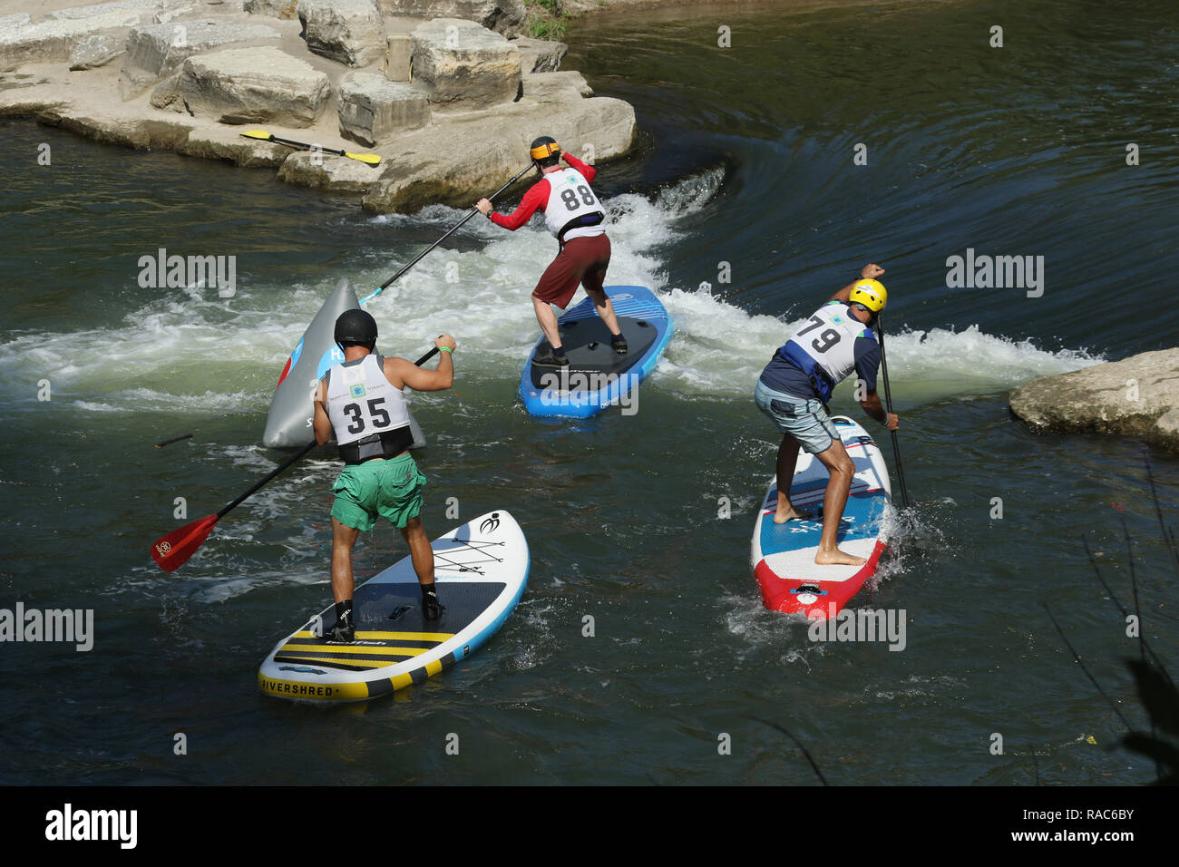Standup Paddleboarders race around a buoy. At the Whitewater feature in ...