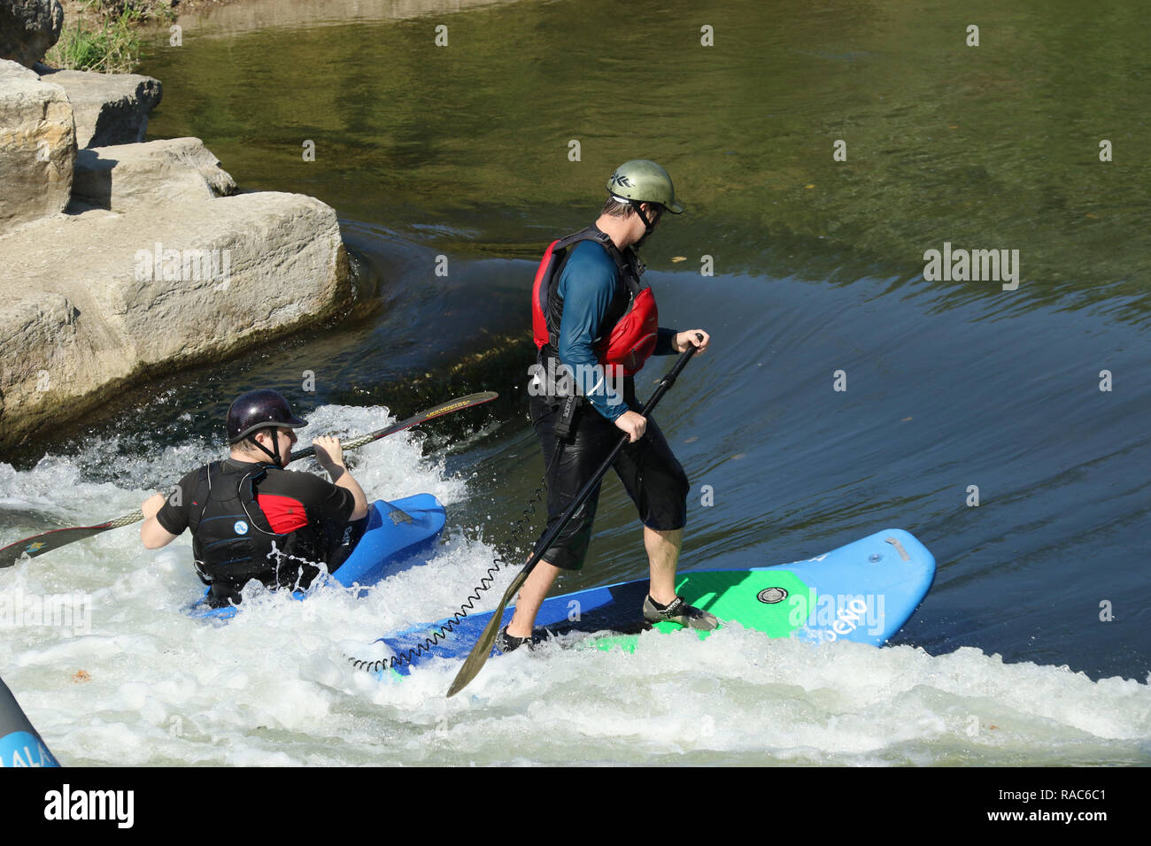 Kayaker and Standup Paddleboarder rides in a water trough. At the ...