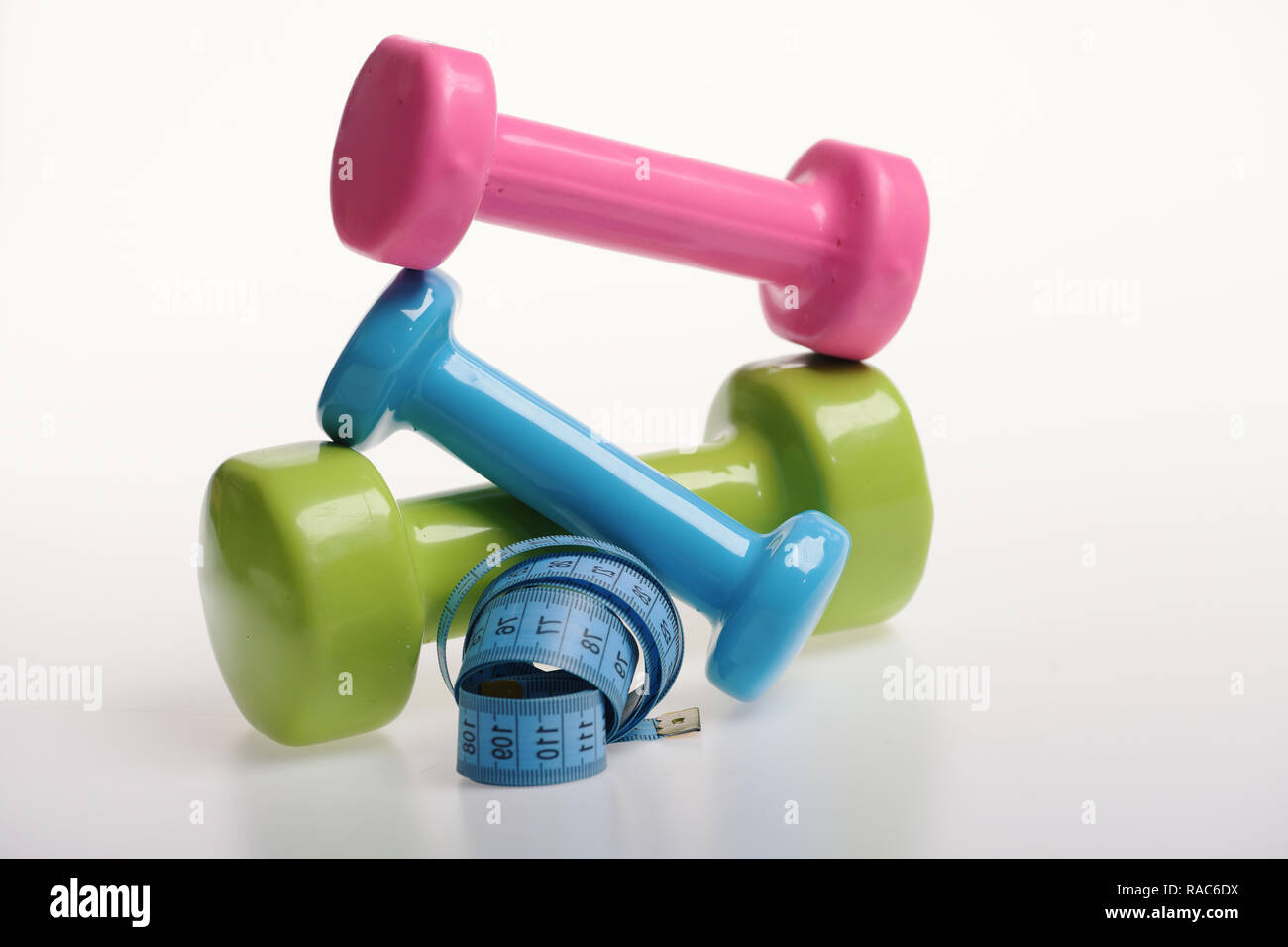 Dumbbells near blue rolled ruler on white background. Measure tape and ...