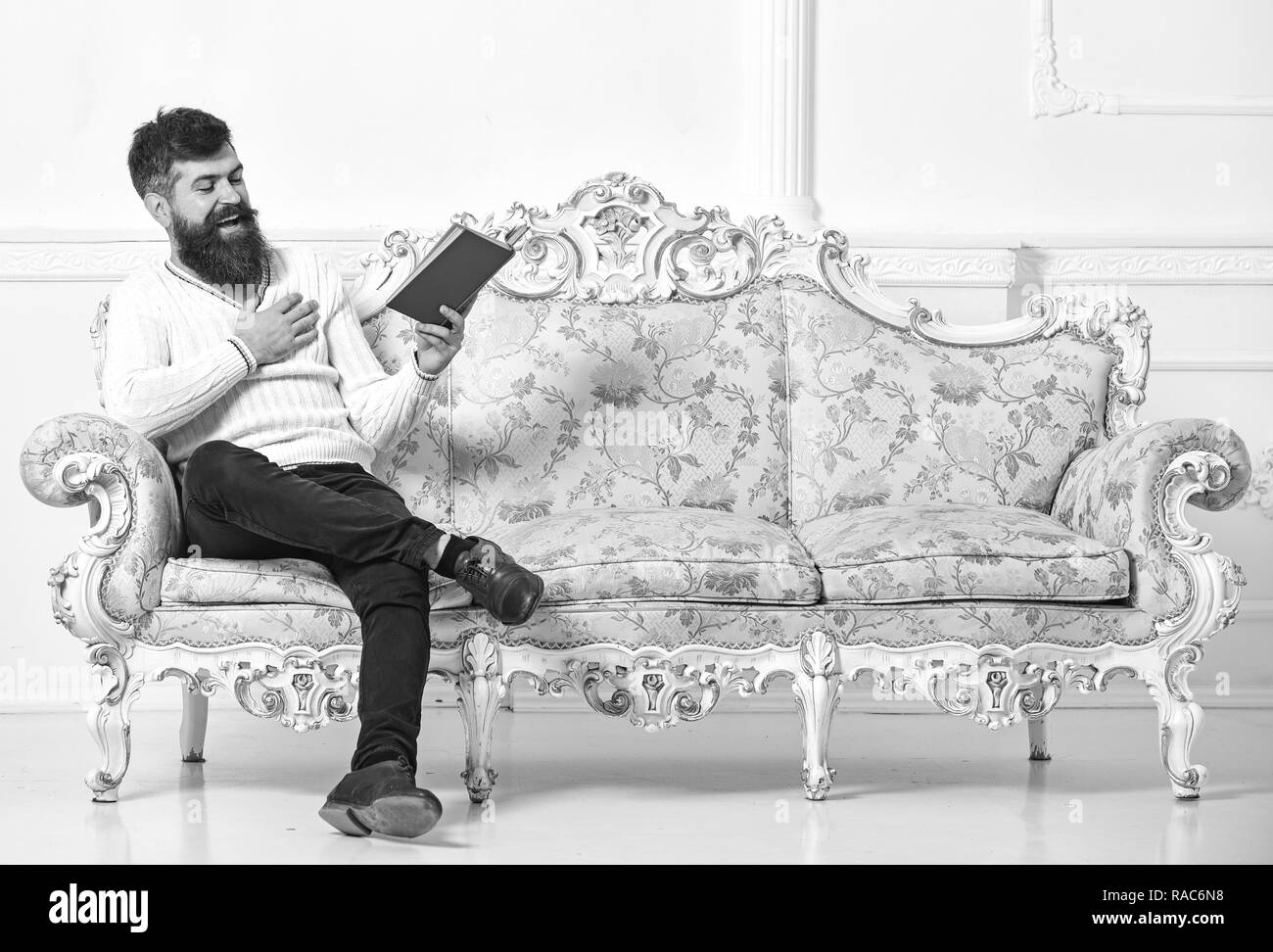 Guy reading old book with enjoyment. Man with beard and mustache sits ...