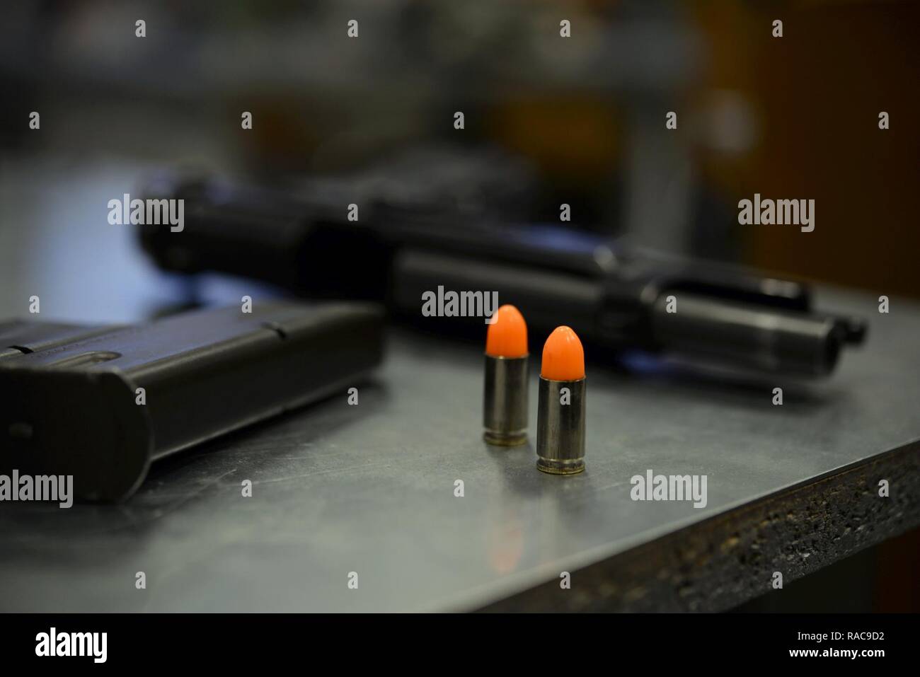 A Beretta M9 handgun and pair of training rounds rest on a table at the ...