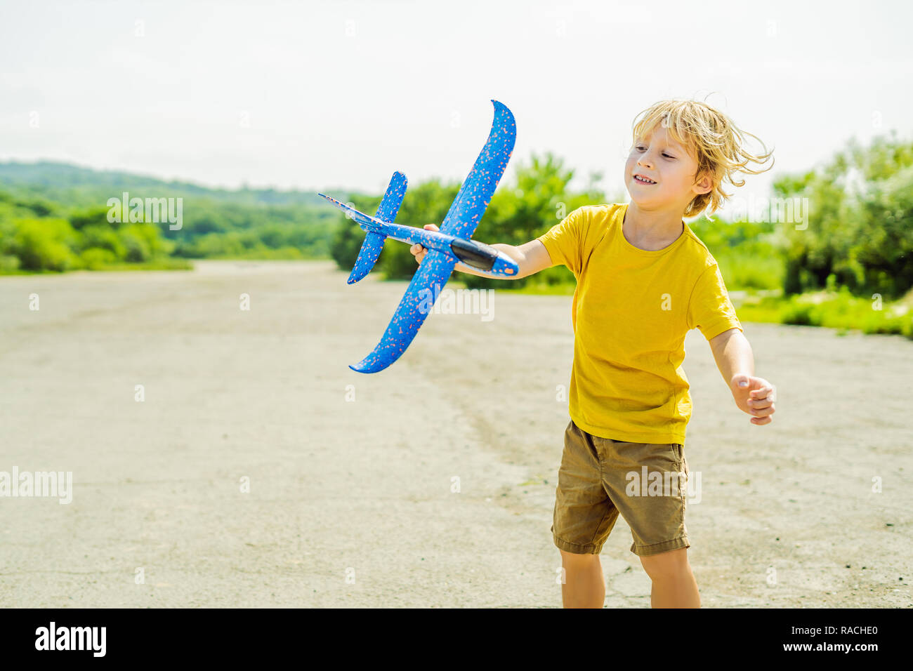 Happy kid playing with toy airplane against old runway background ...