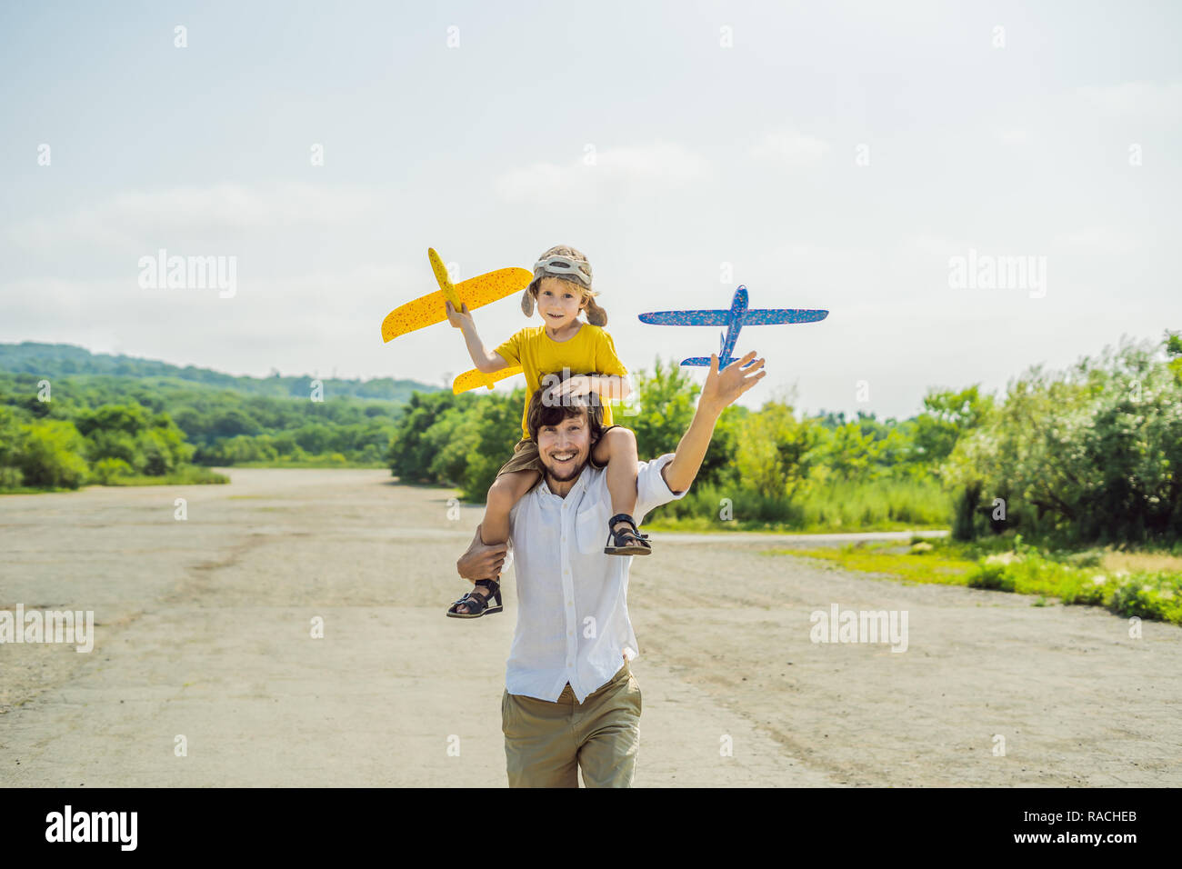 Happy father and son playing with toy airplane against old runway ...