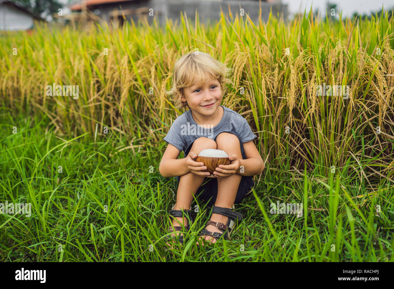Boy is holding a cup of boiled rice in a wooden cup on the background ...