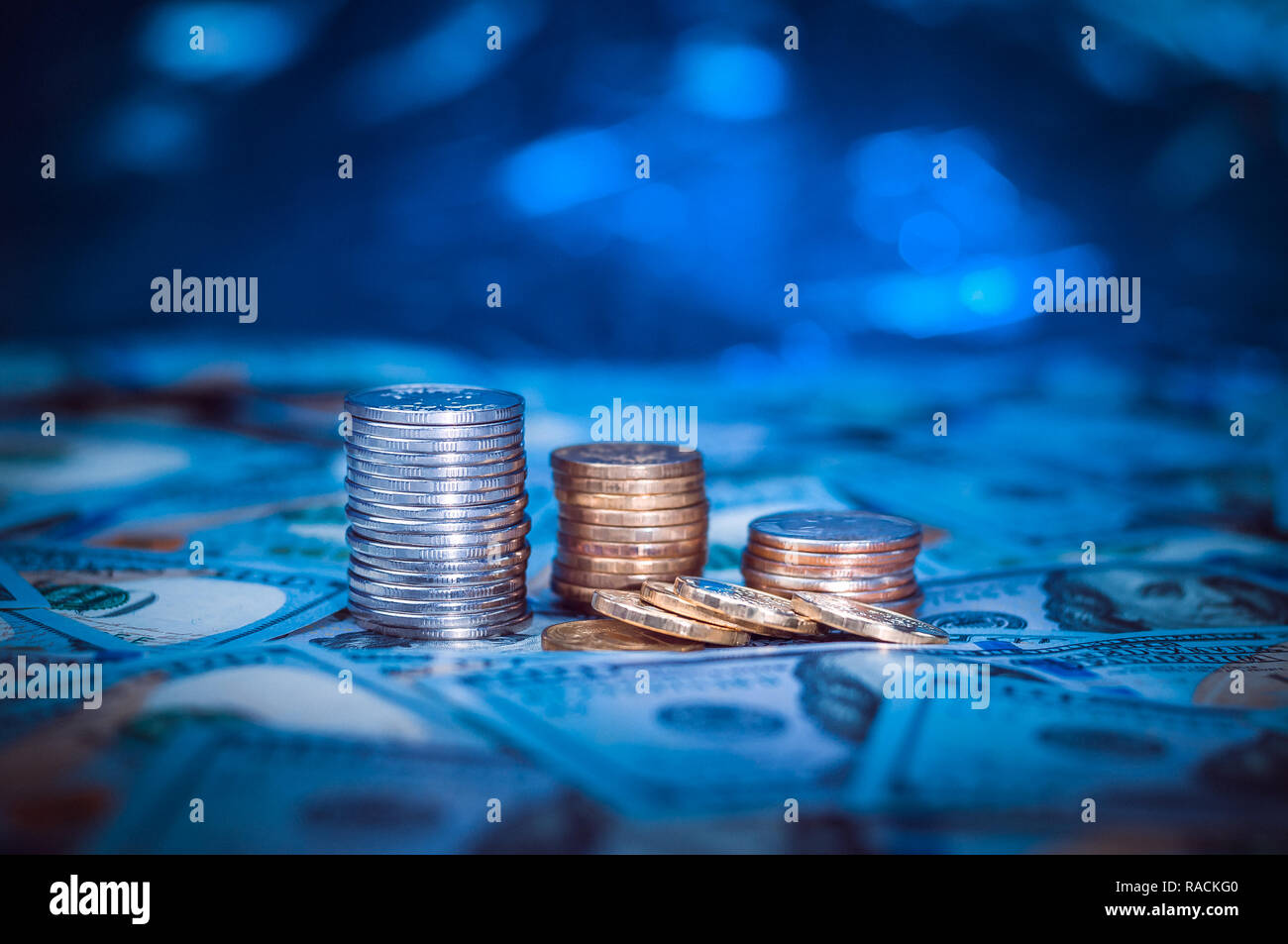 Stacks of coins on the background of one hundred dollar bills. Dark ...