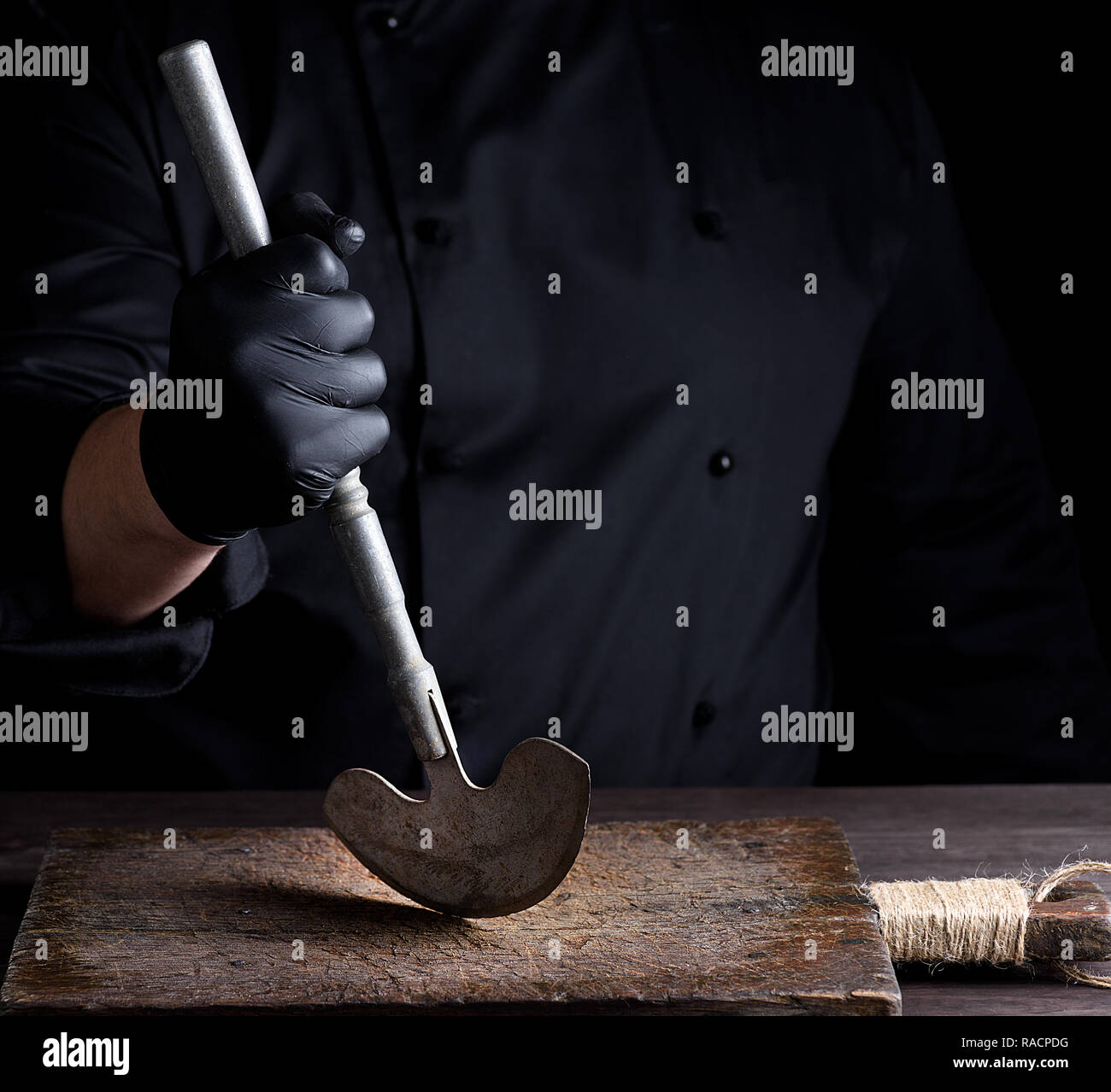 chef in black clothes holds in his hand a metal old knife for meat and ...