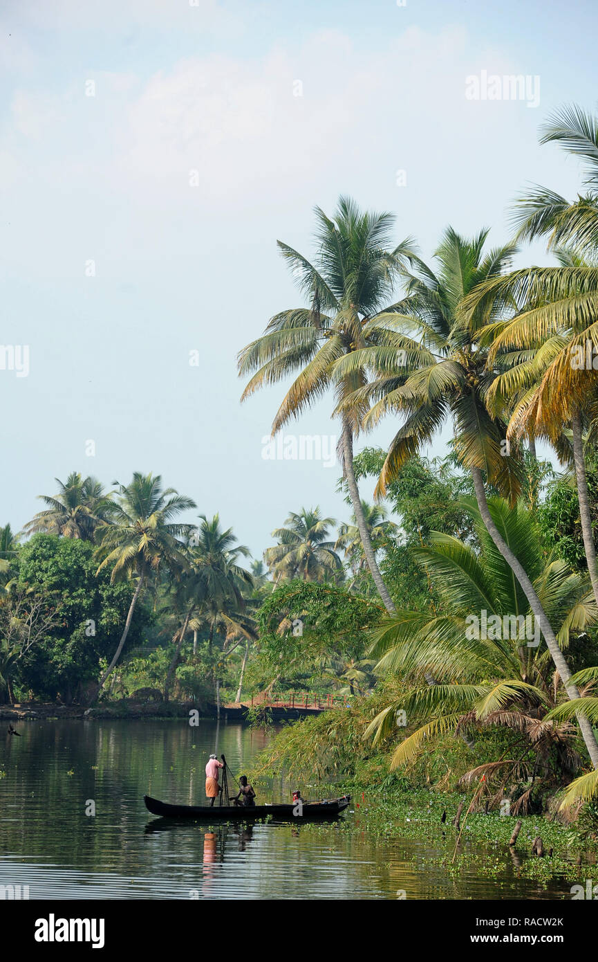 Kerala boatman ferrying local villagers across the backwaters in wooden ...