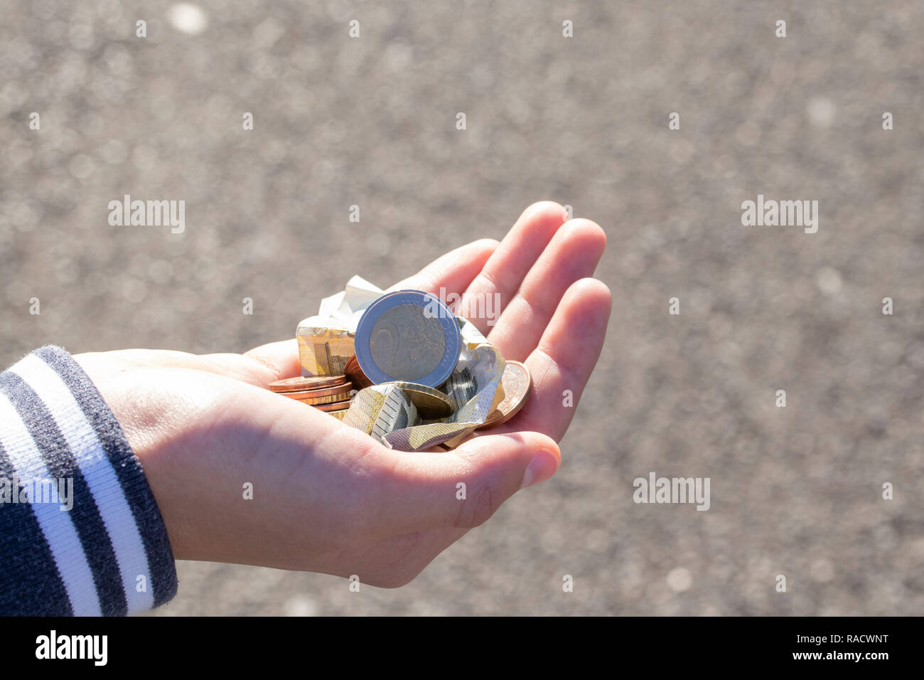 A child holds coins and euro notes in his hands. Pocket money image ...
