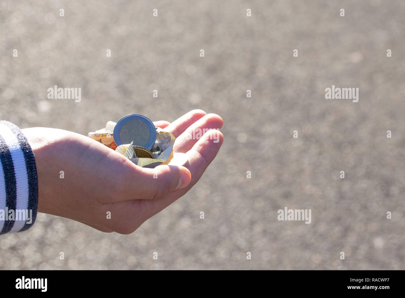 A child holds coins and euro notes in his hands. Pocket money image ...