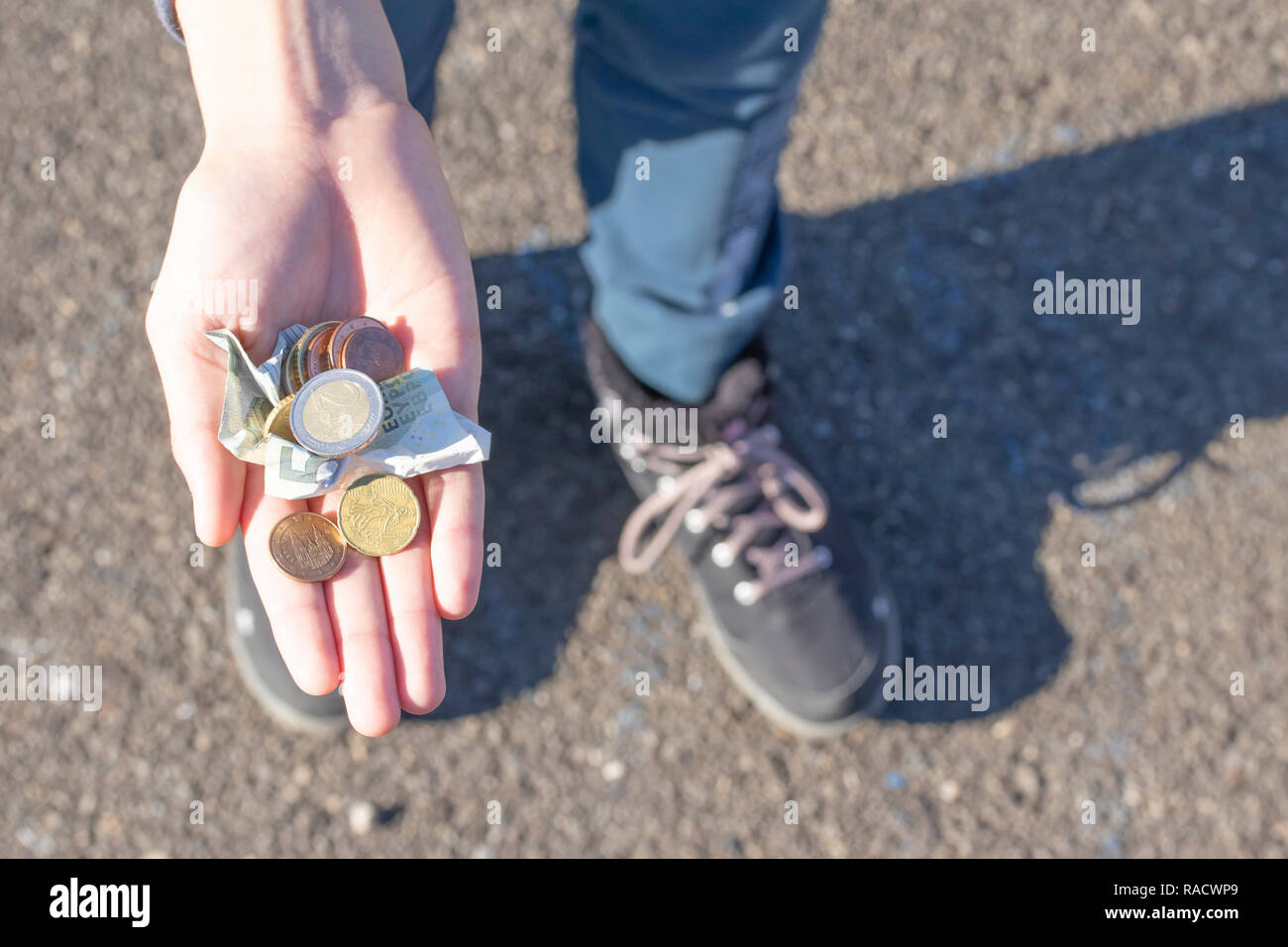 A child holds coins and euro notes in his hands. Pocket money image ...