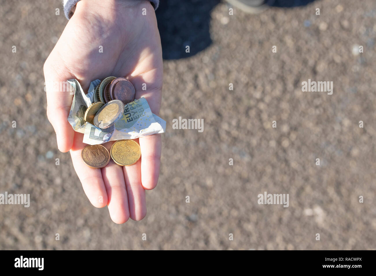 A child holds coins and euro notes in his hands. Pocket money image ...