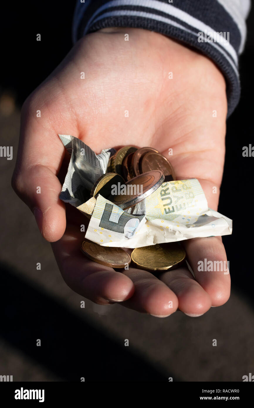 A child holds coins and euro notes in his hands. Pocket money image ...