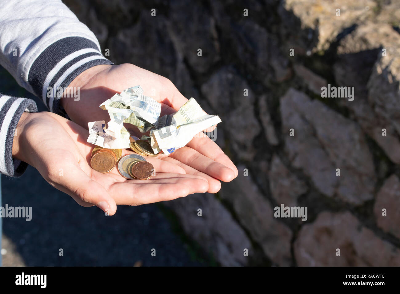 A child holds coins and euro notes in his hands. Pocket money image ...
