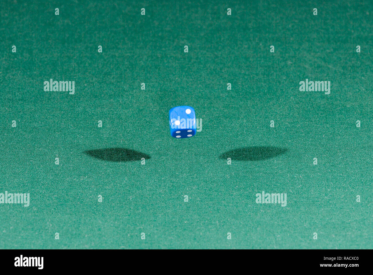 One blue dice falling on a green table Stock Photo - Alamy