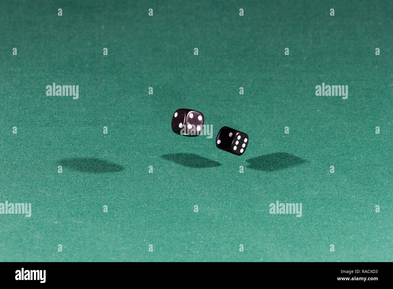 Two black dices falling on a green table Stock Photo - Alamy