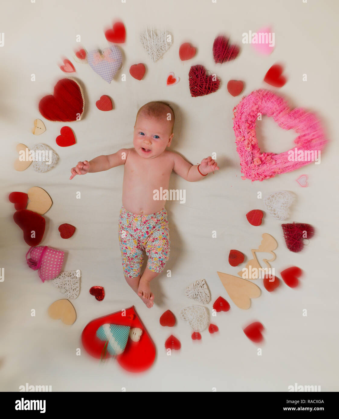 Lovely child. Small girl among red hearts. Love. Portrait of happy ...