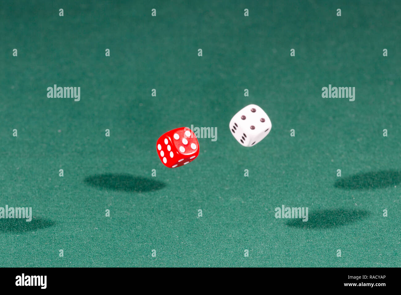 Two red and white dices falling on a green table Stock Photo - Alamy