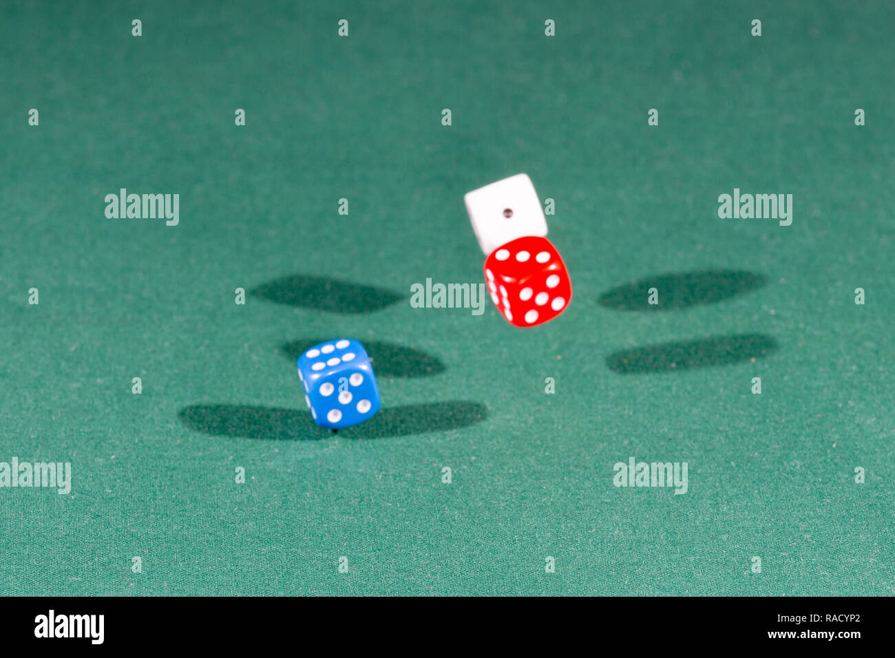 White, red and blue dices falling on a green table Stock Photo - Alamy
