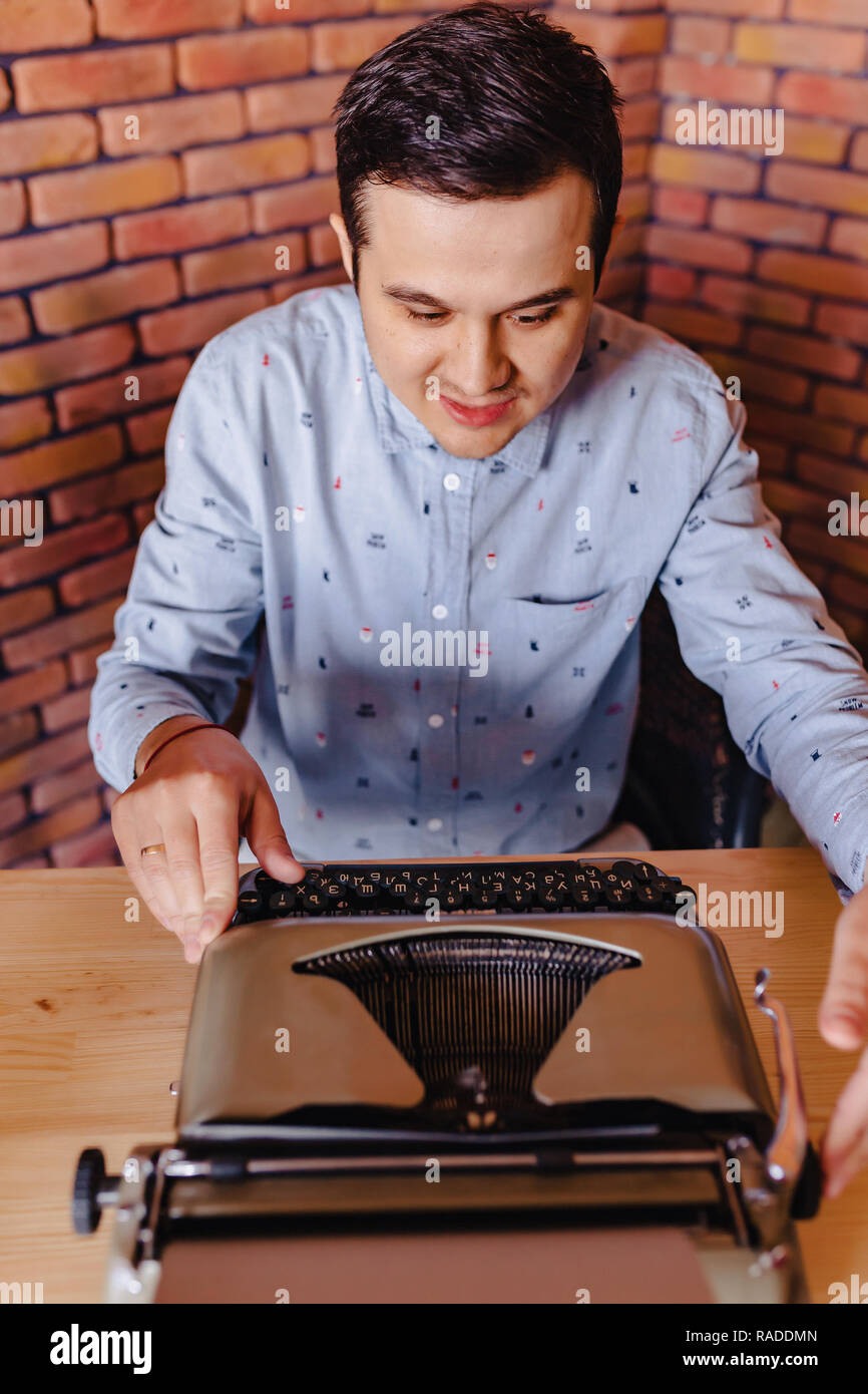 stylish man is sitting on a typewriter in a festive mood with a glass ...