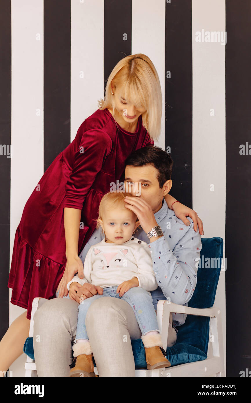 beautiful family with a small daughter, a simple background, happiness ...