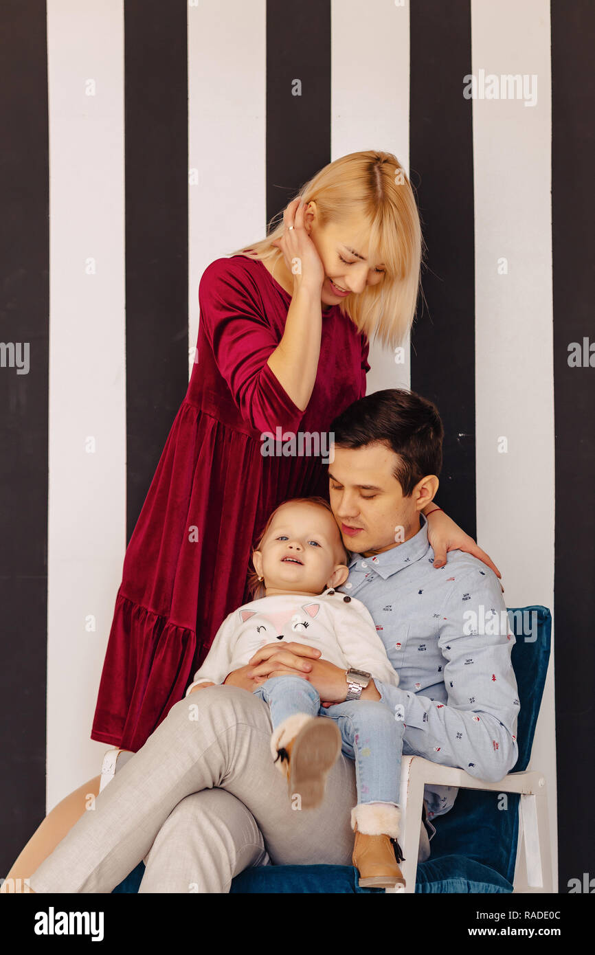 beautiful family with a small daughter, a simple background, happiness ...