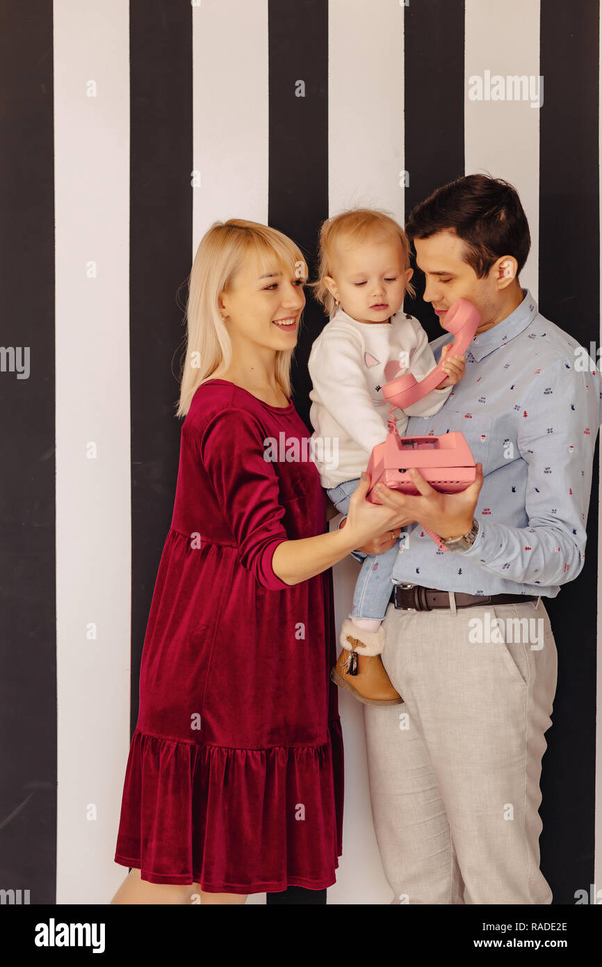 beautiful family with a small daughter talking by rose retro phone, a ...