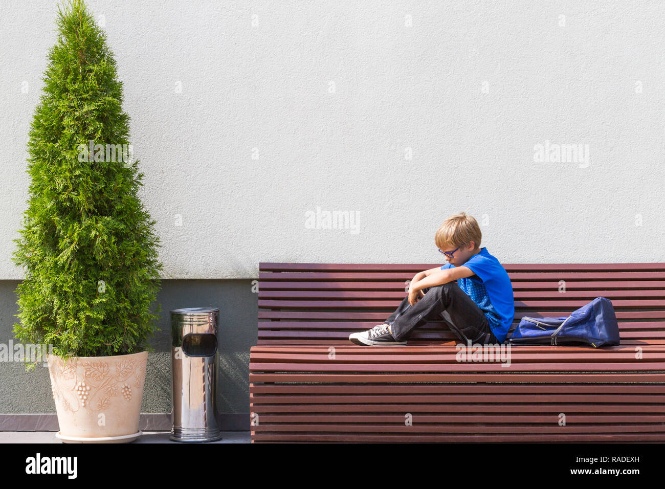 Sad, tired child sitting alone on the bench outdoors Stock Photo - Alamy
