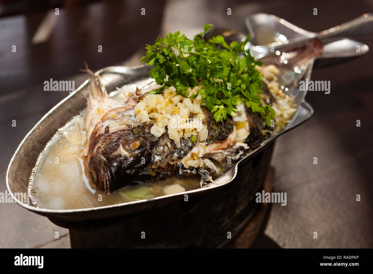 Grilled whole fish with fresh coriander and spices with lemon sauce on ...