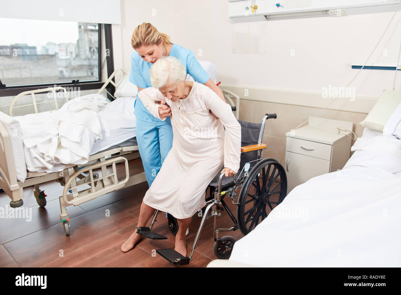 Nurse helps elderly woman with disability in a wheelchair in nursing ...