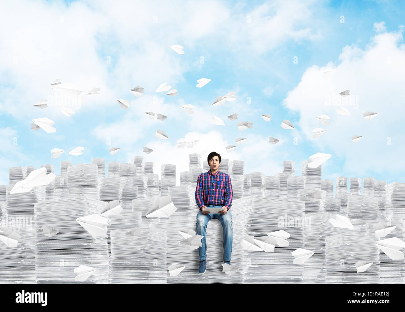 Attractive man sitting on pile of paper documents Stock Photo - Alamy