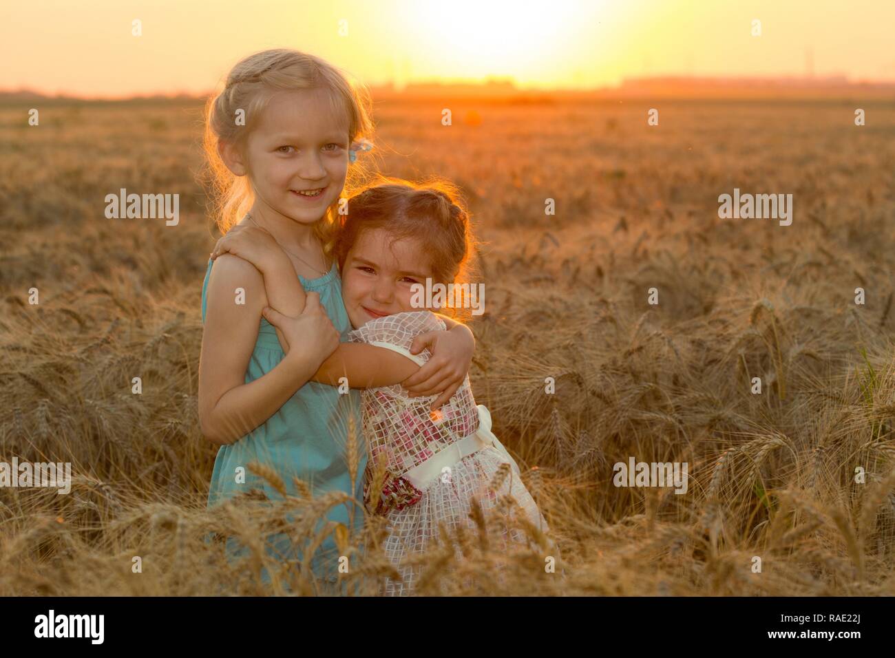 two children girls are looking at the sunset at the wheat field Stock ...