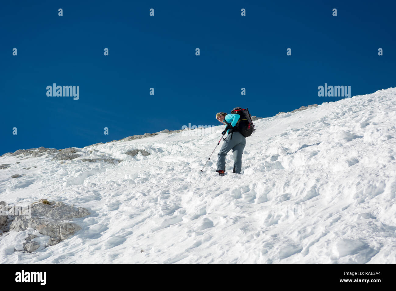 Female alpinist ascending a steep snowy slope Stock Photo - Alamy
