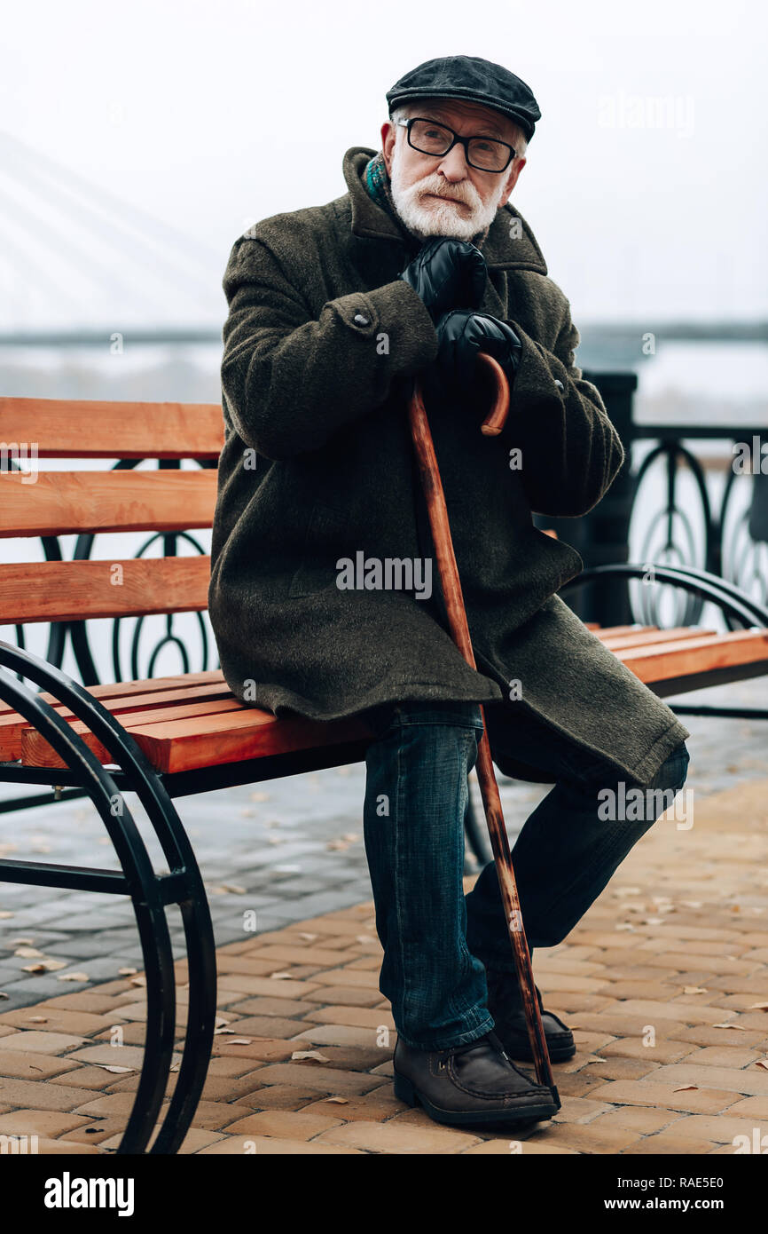 Serious male person sitting on bench alone Stock Photo - Alamy
