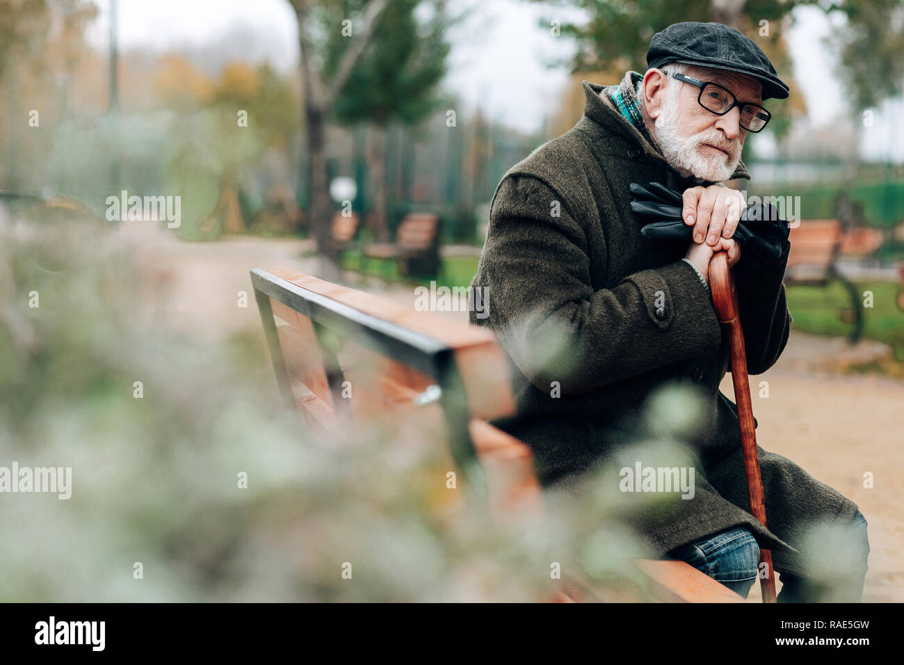 Sad retired man sitting alone on bench Stock Photo - Alamy