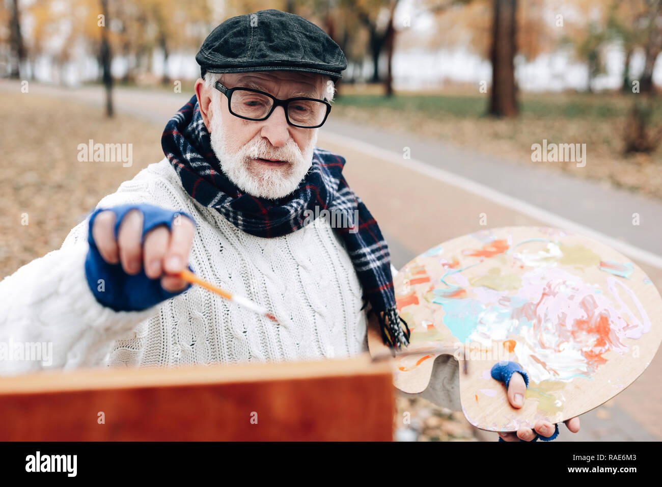 Concentrated senior male person creating modern picture Stock Photo - Alamy