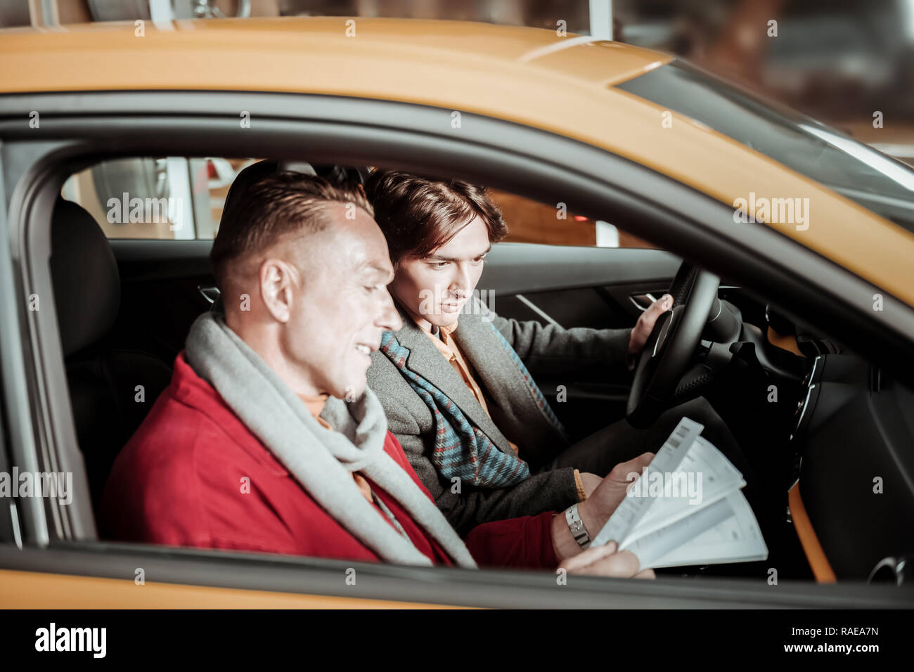 Stylish good-looking father and son sitting in their new future car ...