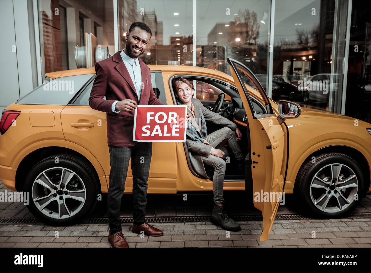 African-American sales manager selling nice passenger orange car Stock ...