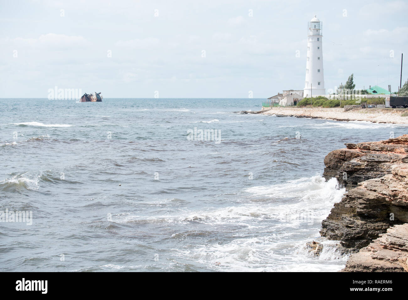 Landscape of waves in sea and piece of coast with lighthouse on it ...