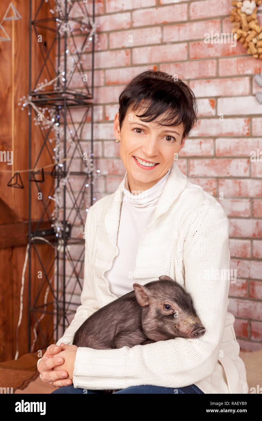 Little black piggy in hands of surprised, attractive young female model ...