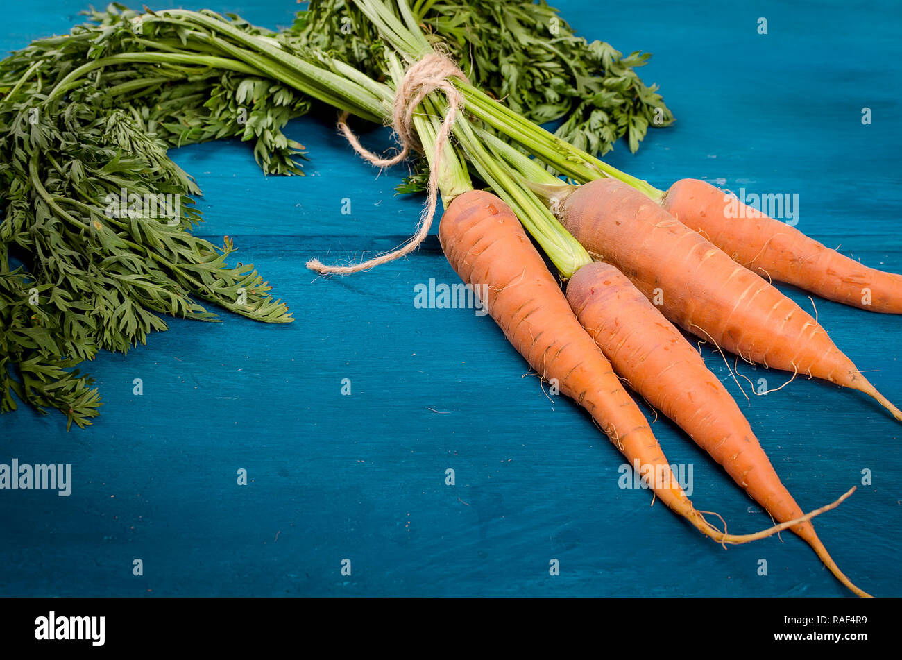 Bunch of fresh carrots with green leaves over old blue wooden ...