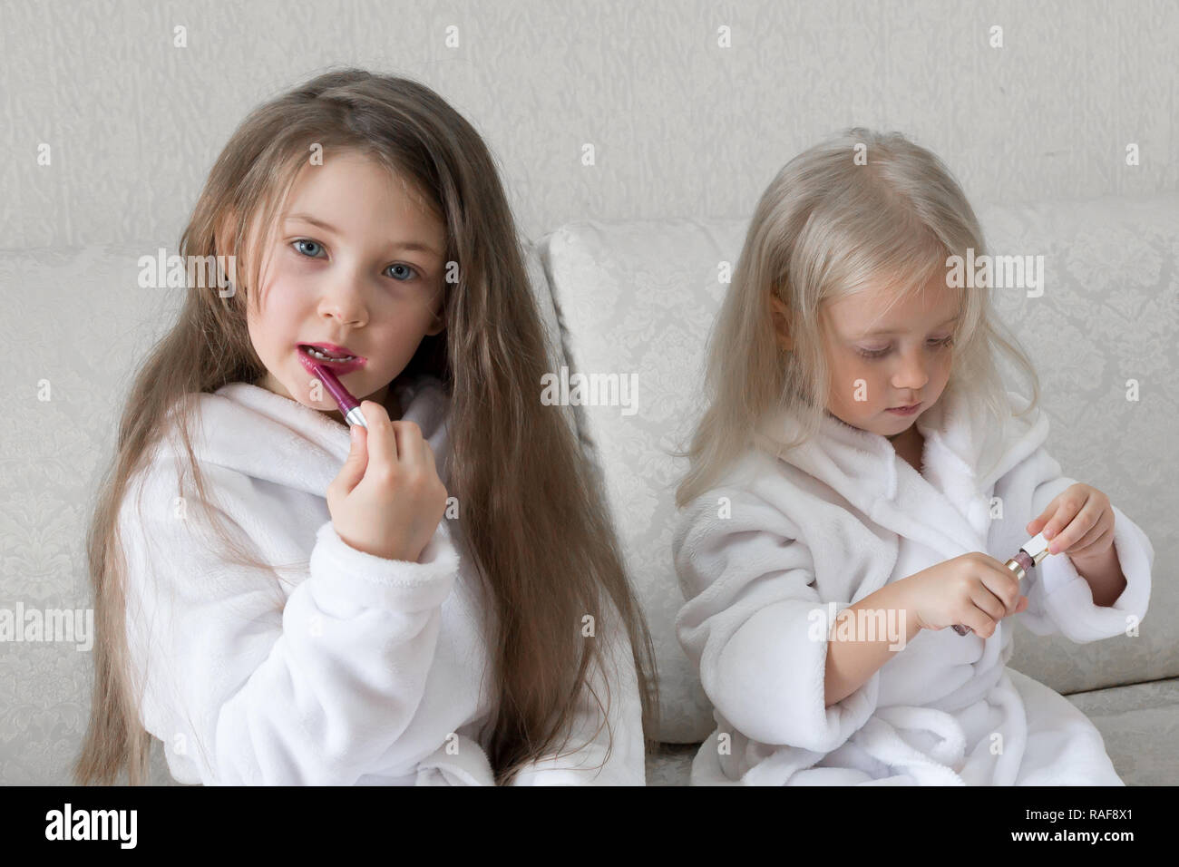 Two little girls in white coats after a shower playing with makeup ...