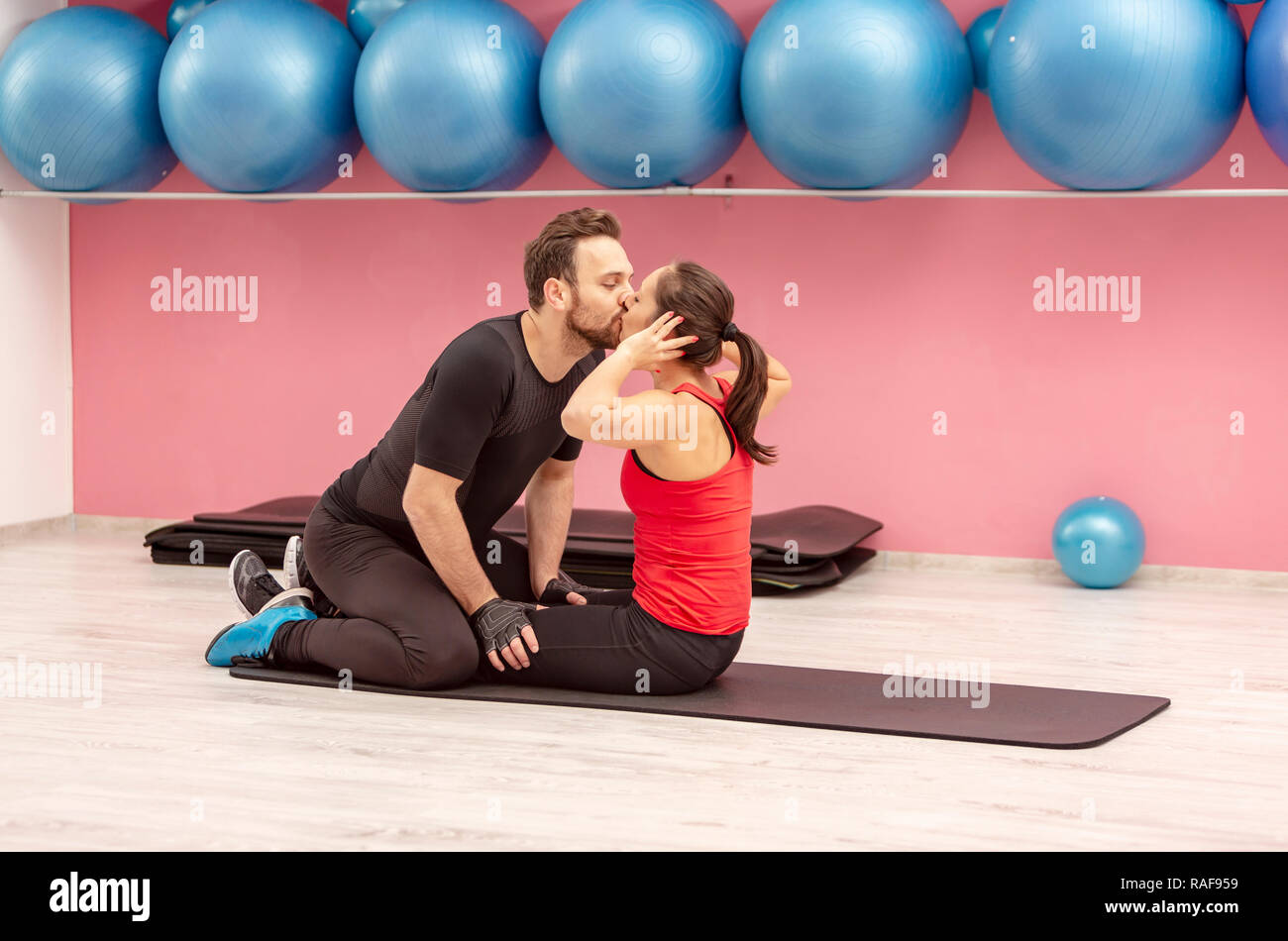 Young couple kissing in a gym while doing exercises together Stock ...
