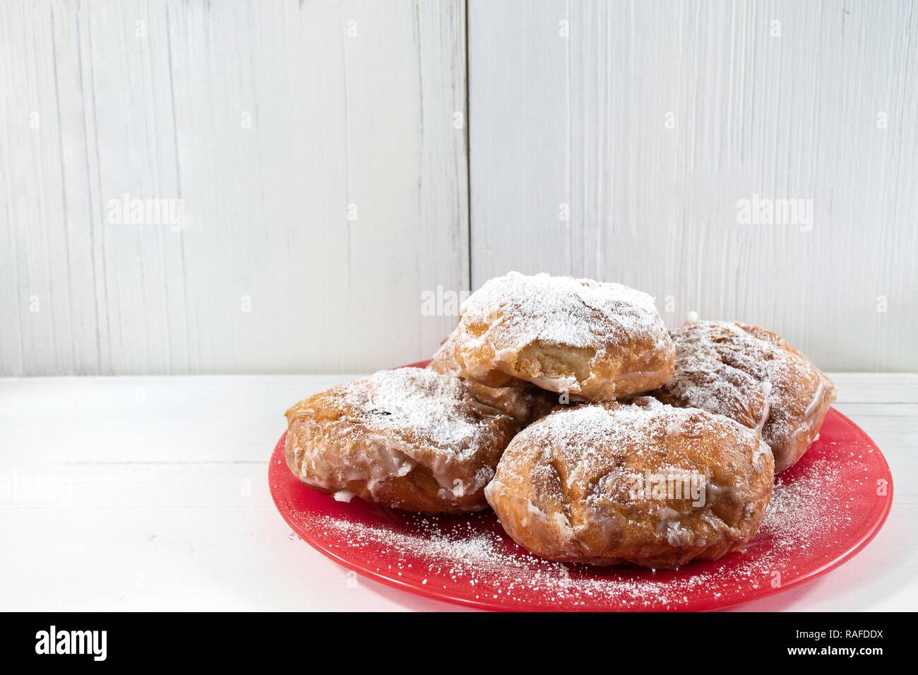 Dutch fat balls with powdered sugar on red plate and rustic whitewashed ...