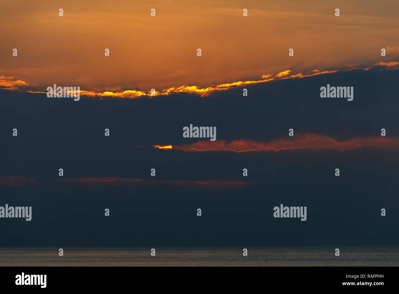 The sun disappearing behind cloud-cover Stock Photo - Alamy