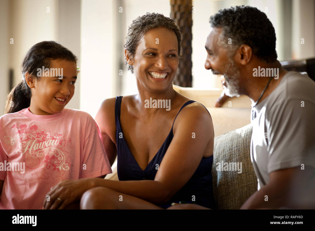 Parents laughing with daughter on couch Stock Photo - Alamy
