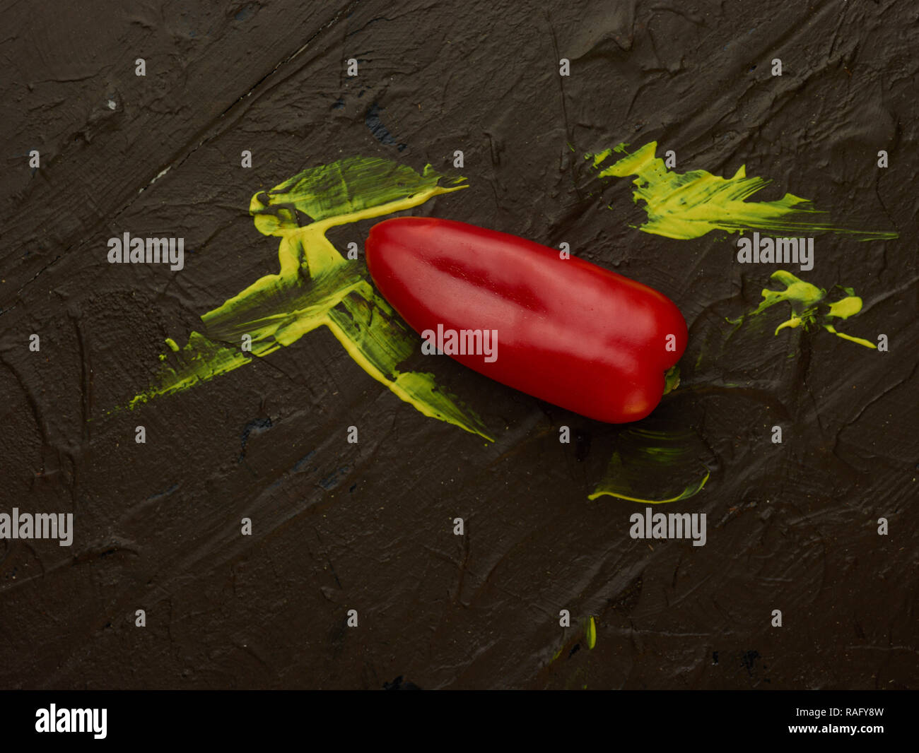 Single red mini sweet pepper against dark background with yellow flecks ...